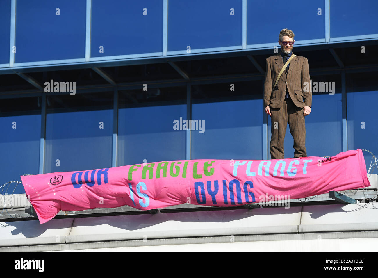 A protester stands on the roof of the terminal building at City Airport ...