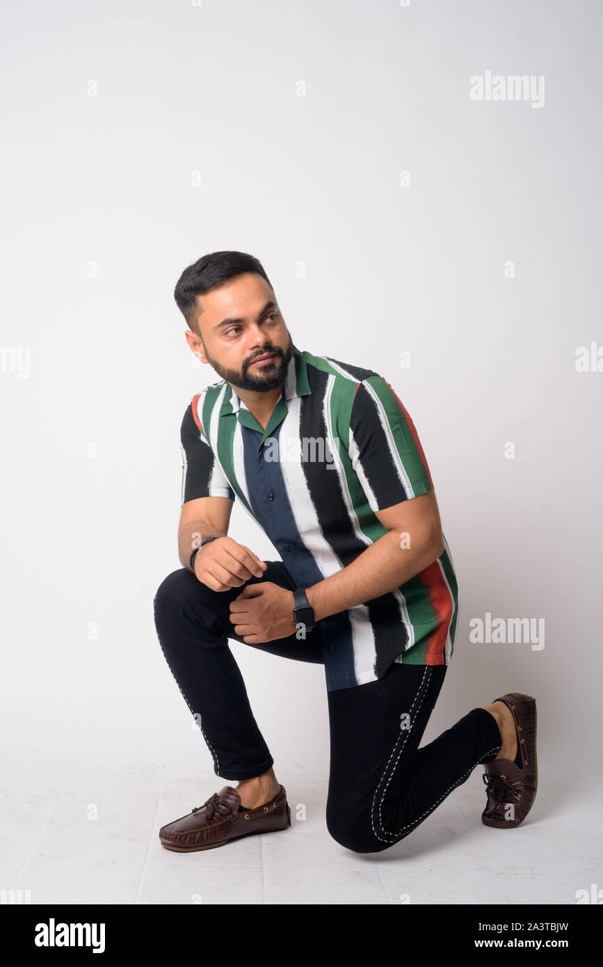 Full body shot of young bearded Indian man crouching and thinking Stock ...