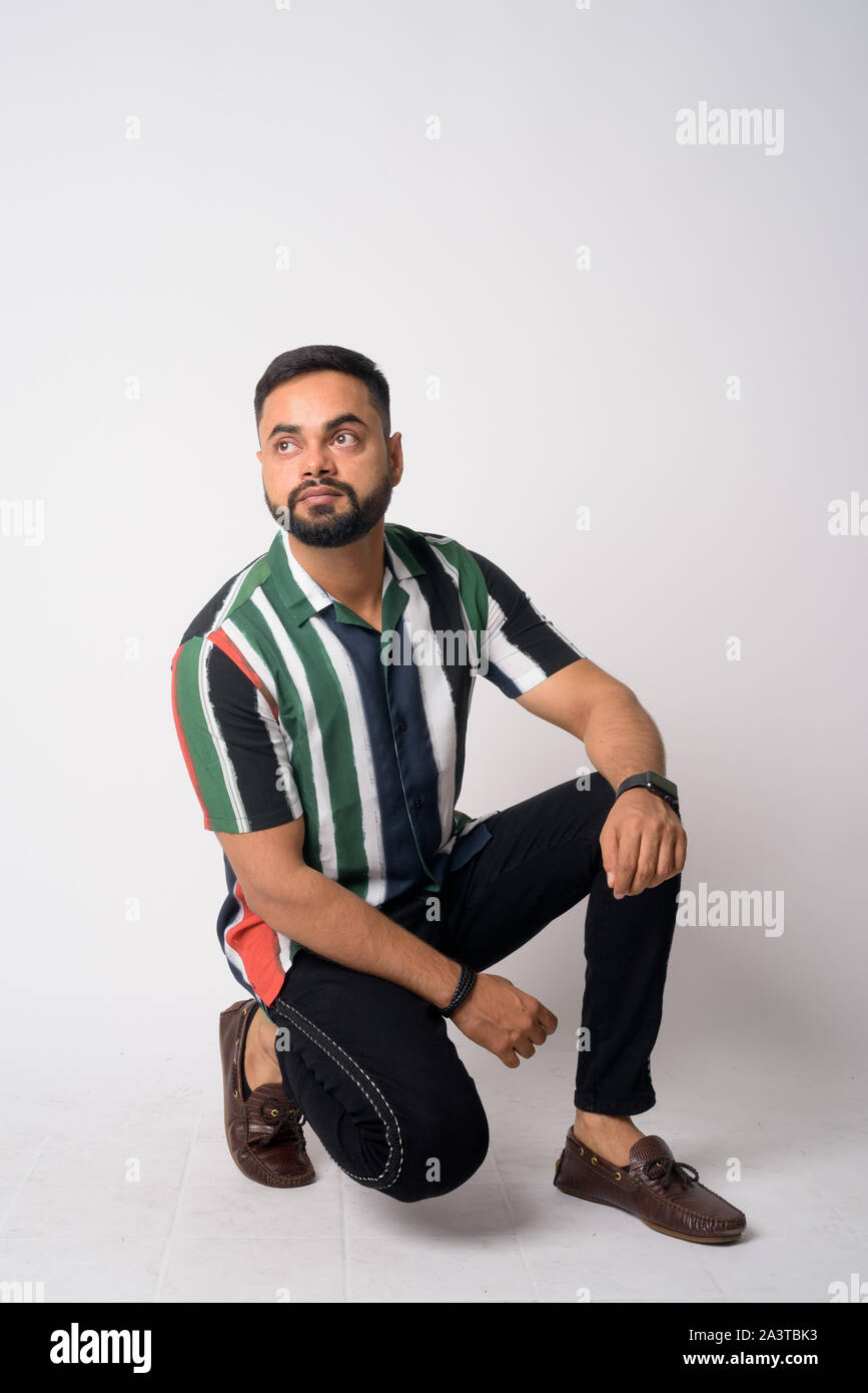 Full body shot of young bearded Indian man crouching and thinking Stock ...