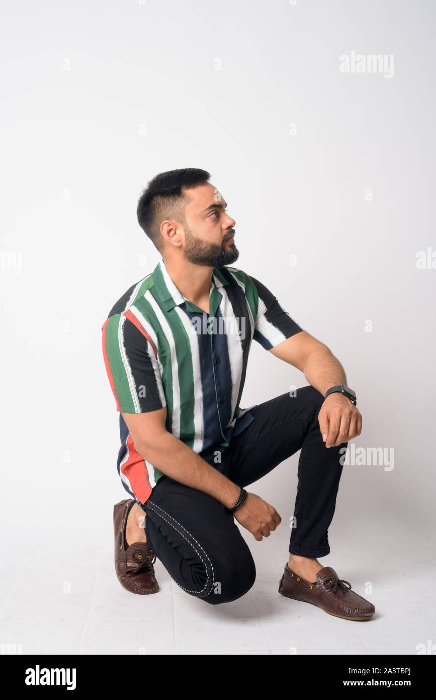 Full body shot of young bearded Indian man crouching and thinking Stock ...