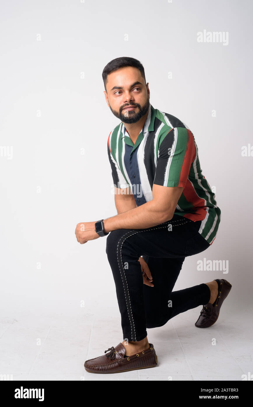 Full body shot of young bearded Indian man crouching and thinking Stock ...