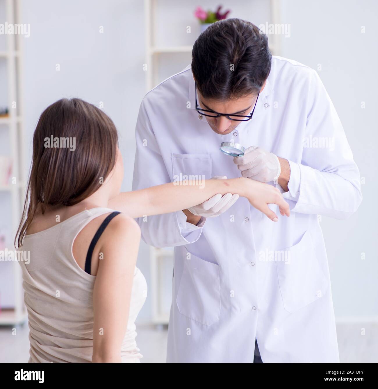 The doctor examining the skin of female patient Stock Photo - Alamy