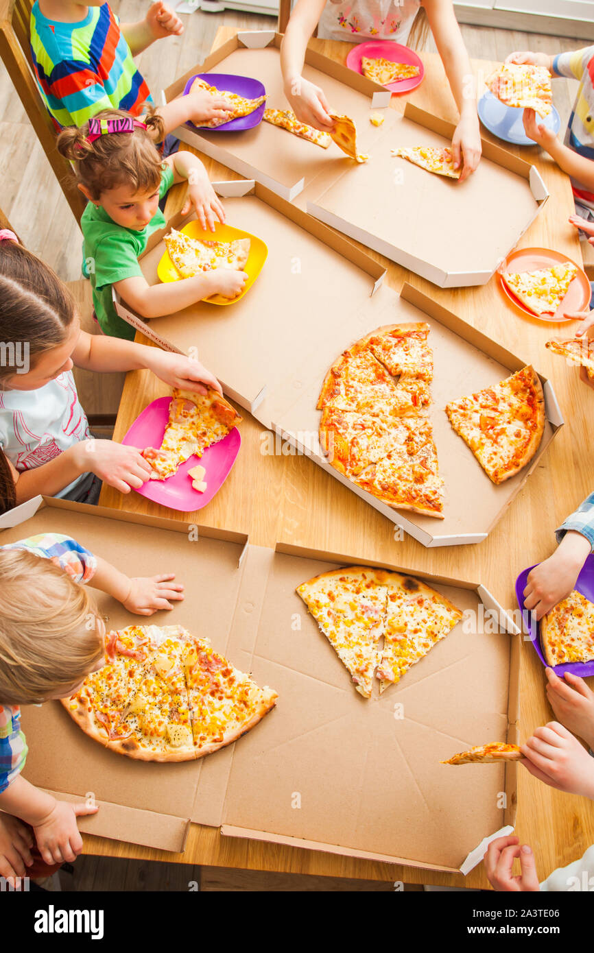 Top view image of children take slices of pizza from box at the kitchen ...
