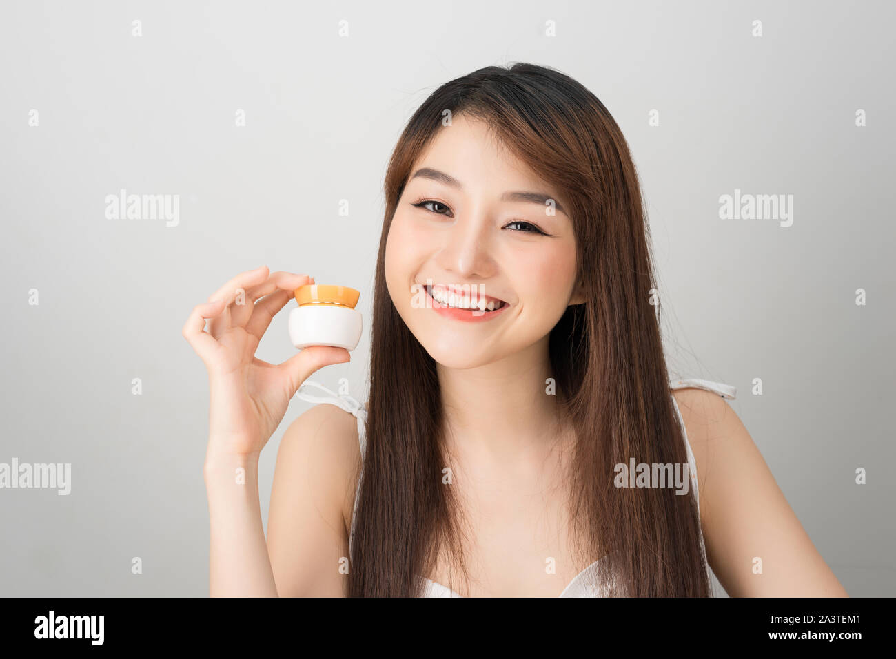 Smiling young asian woman showing skincare product. Beauty concept ...