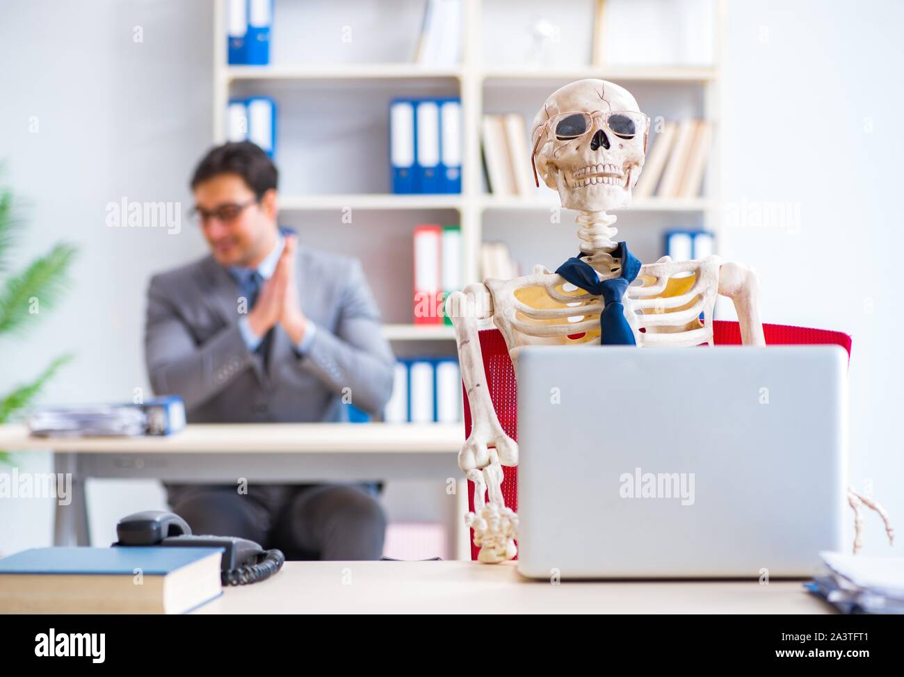 The businessman working with skeleton in office Stock Photo - Alamy
