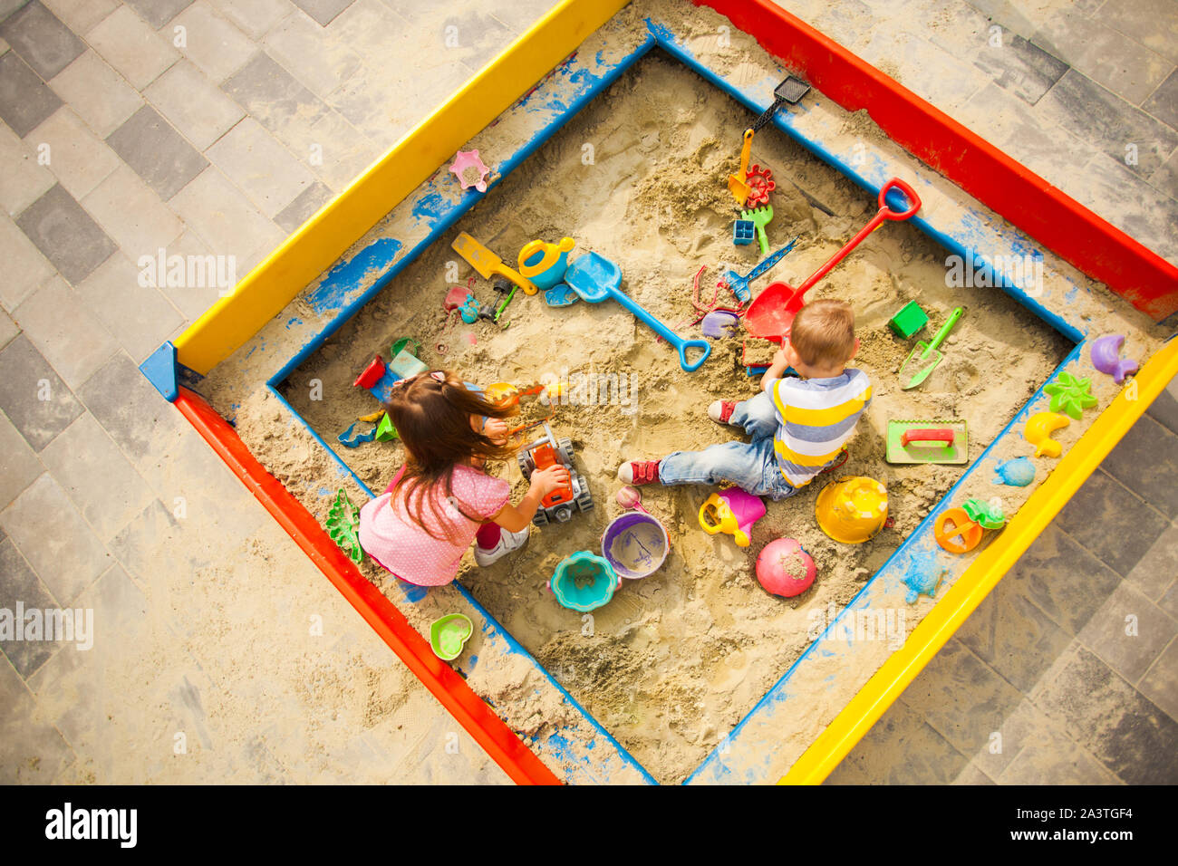 Happy children playing with toys in big sandbox outdoors, top view ...