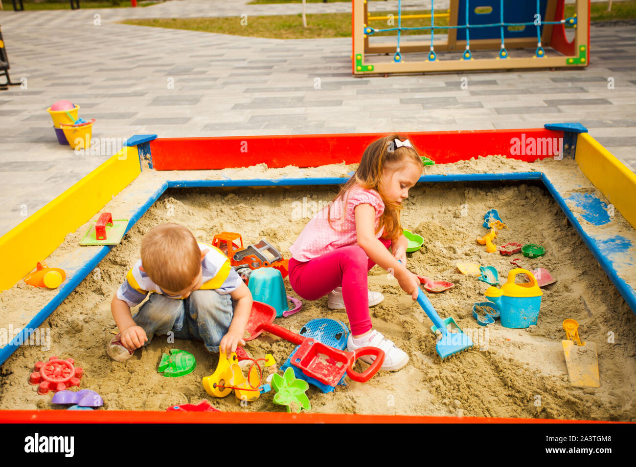 Two children playing in sandbox in sunny day Stock Photo - Alamy
