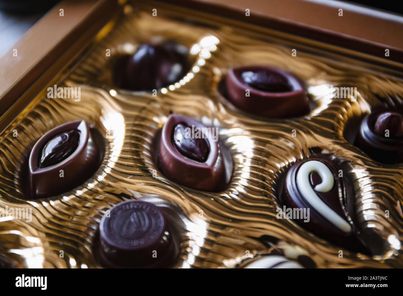 Chocolate candies of different shapes in a gold box, a perspective view ...