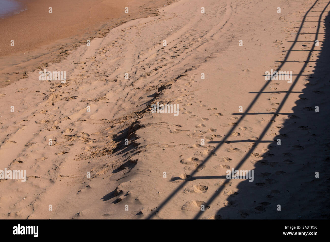 Beach marked with footprints and shadow of fence forming pattern Stock ...