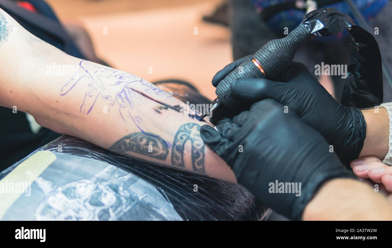 Professional tattoo artist makes a tattoo on a young man’s hand, close ...