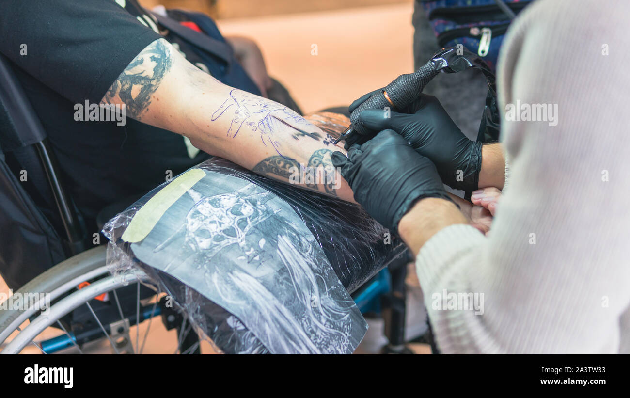 Professional tattoo artist makes a tattoo on a young man’s hand, close ...