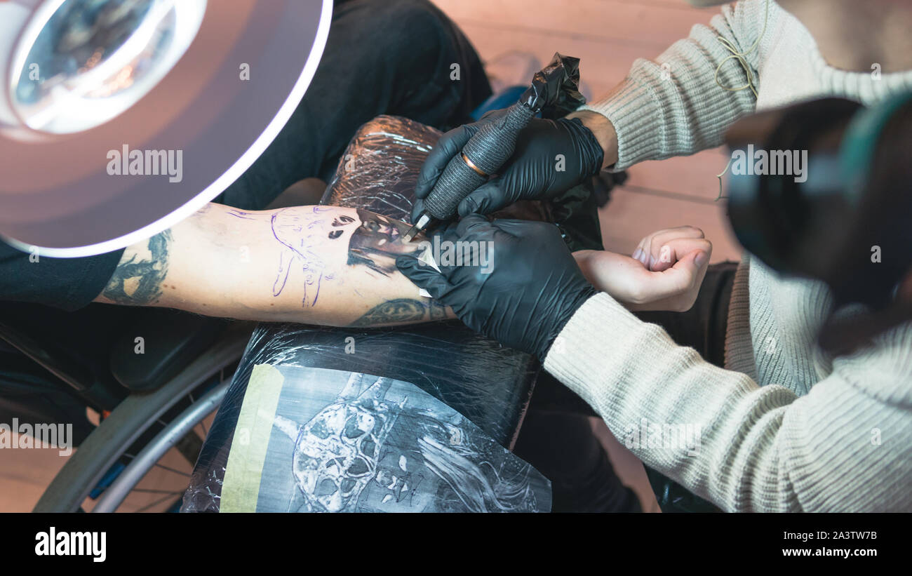 Professional tattoo artist makes a tattoo on a young man’s hand, close ...