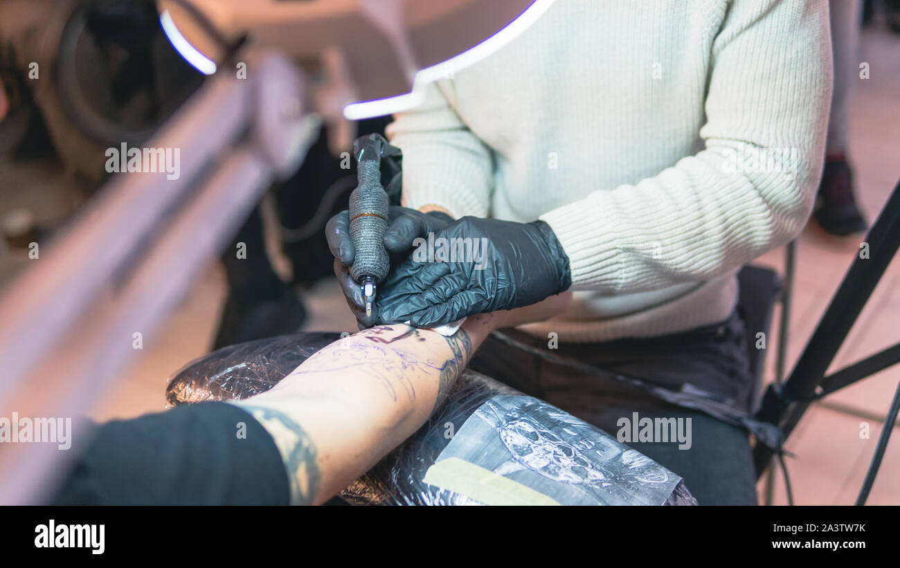 Professional tattoo artist makes a tattoo on a young man’s hand, close ...