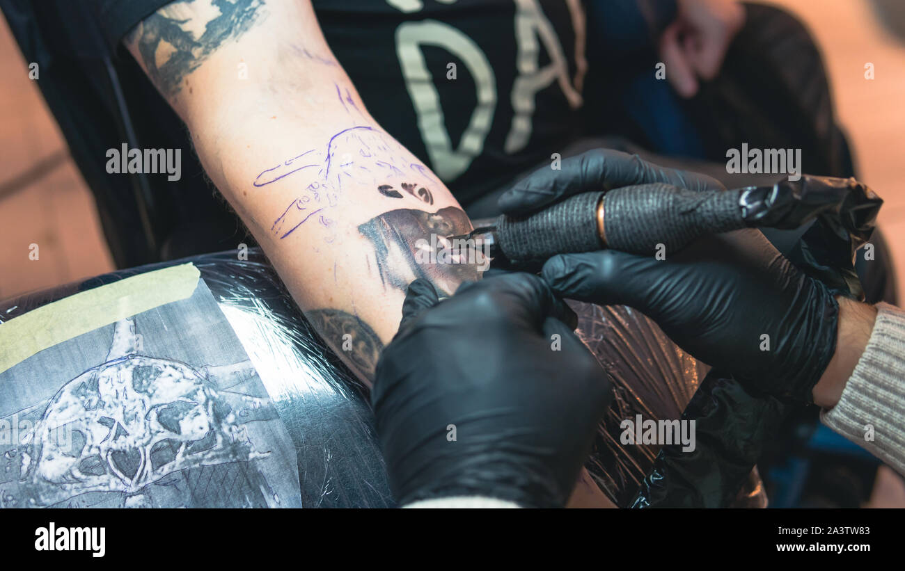 Professional tattoo artist makes a tattoo on a young man’s hand, close ...