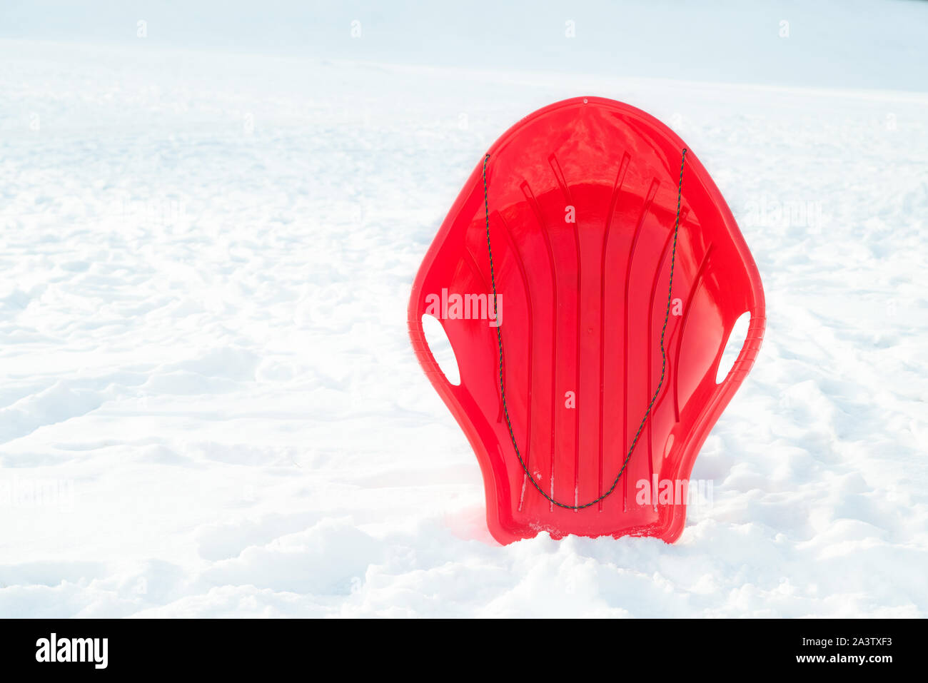 Red plastic sleigh, sledge, sled on white snowy background outdoors ...