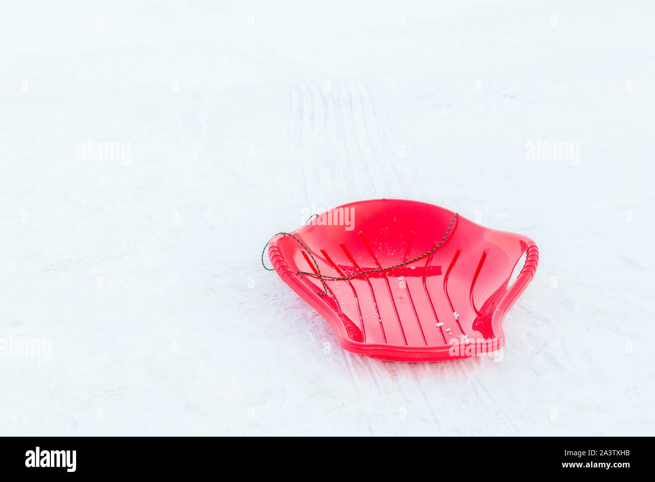 Red plastic sleigh, sledge, sled on white snowy background outdoors ...