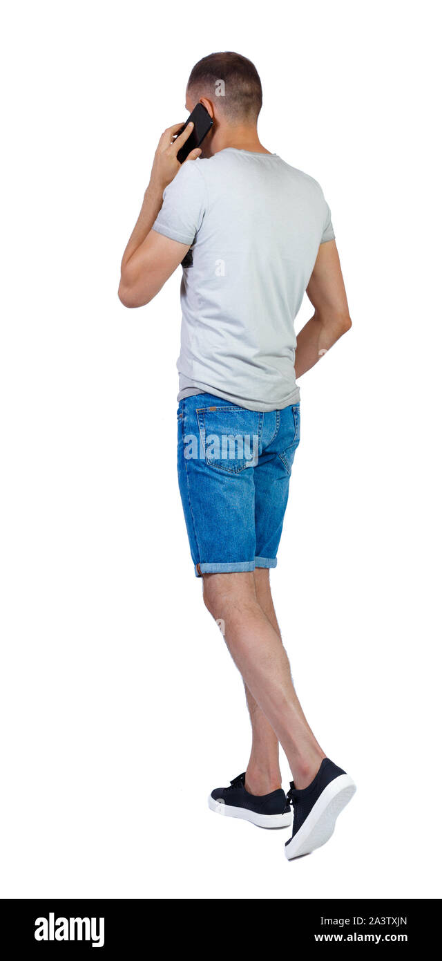 Back view of man in shorts walking with a mobile phone. backside view ...