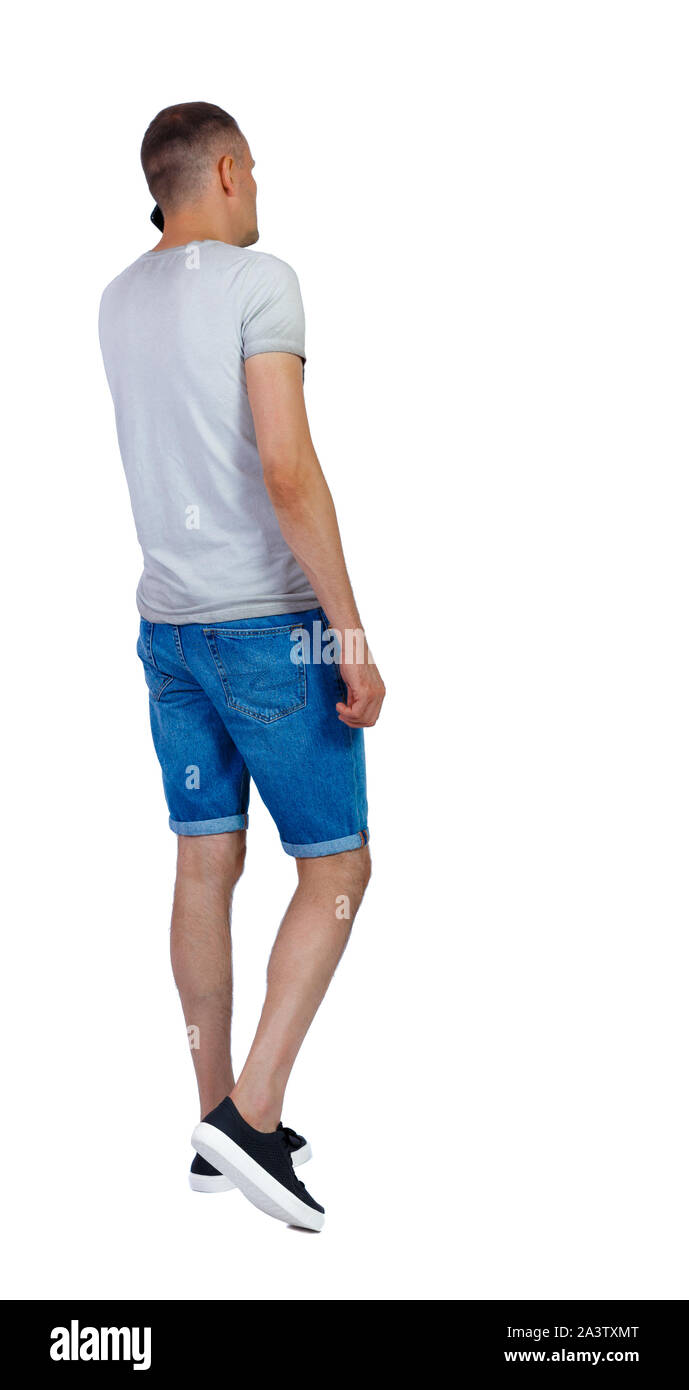 Back view of man in shorts walking with a mobile phone. backside view ...