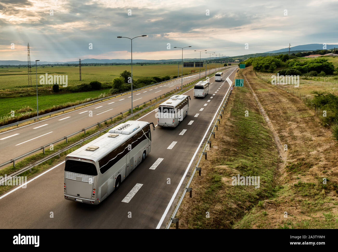 Caravan or convoy of Four buses in line traveling on a highway country ...