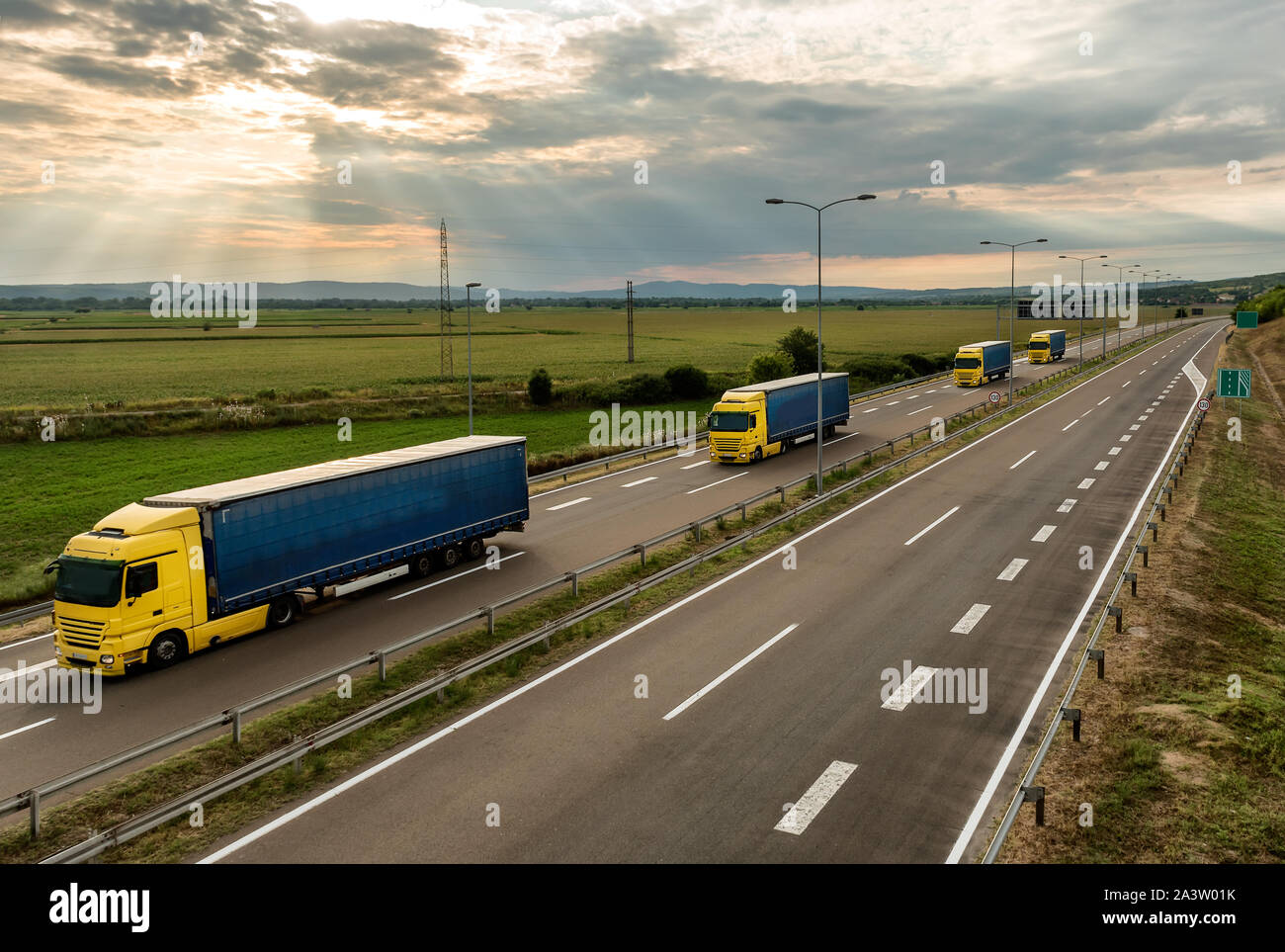 Lorry trucks in line as a caravan or convoy on country highway under a ...