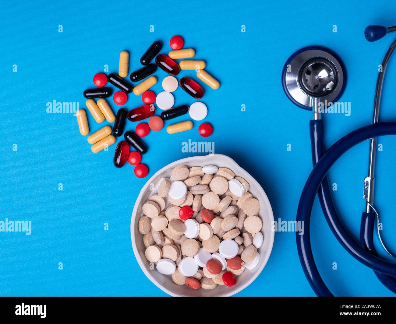 Top view with multicolored pills and capsules next to a stethoscope and ...