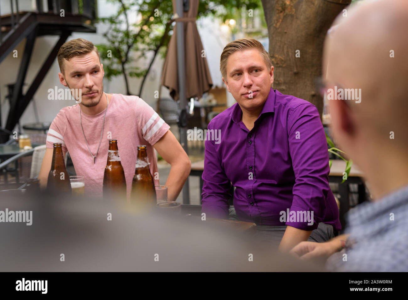 Group of men outdoors sitting and talking together Stock Photo - Alamy