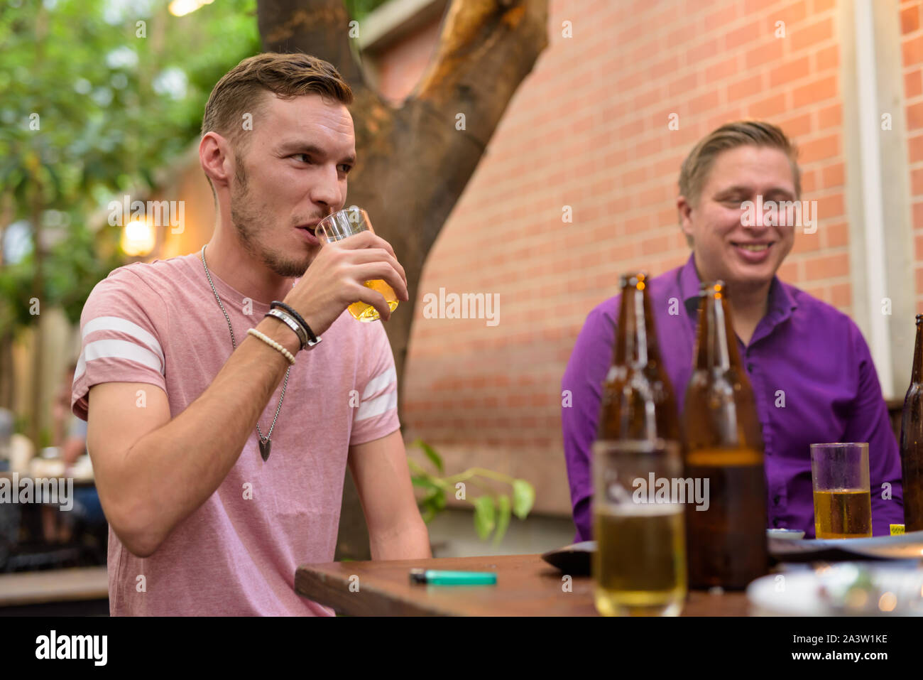 Smiling friends drinking beer together hi-res stock photography and ...