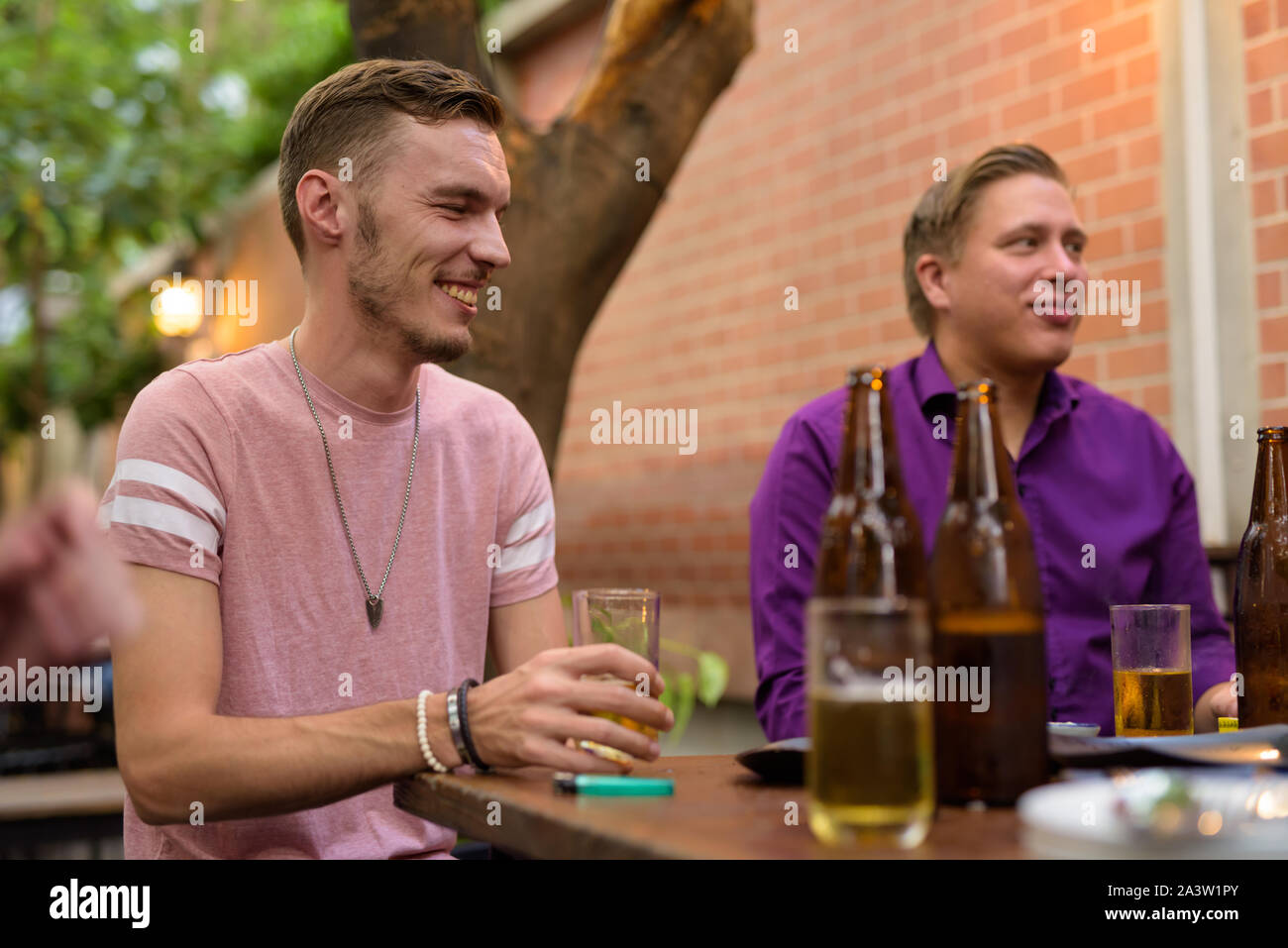 Happy man talking and drinking beer with friends Stock Photo - Alamy