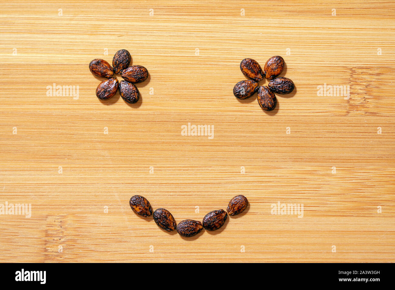 watermelon seeds on wooden background, smiley face Stock Photo - Alamy