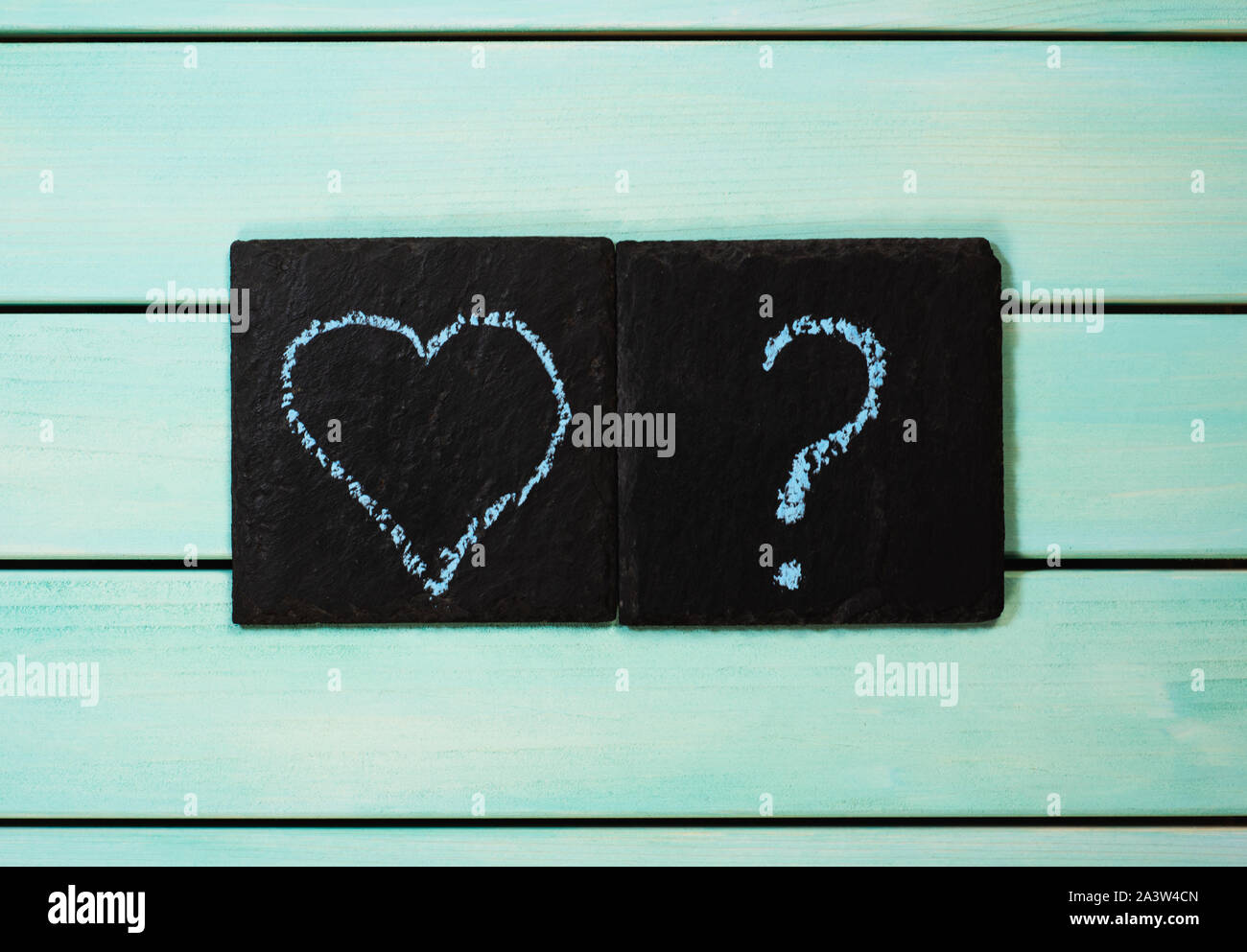 Heart and question mark drawn with chalk, blue wooden background, love ...