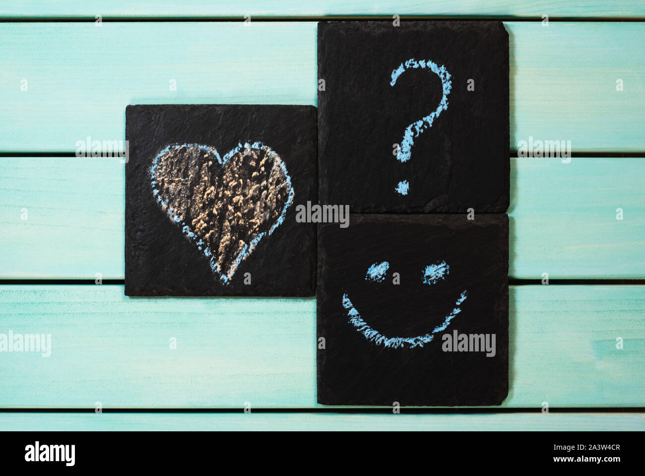 Heart smile and question mark drawn with chalk, blue wooden background ...