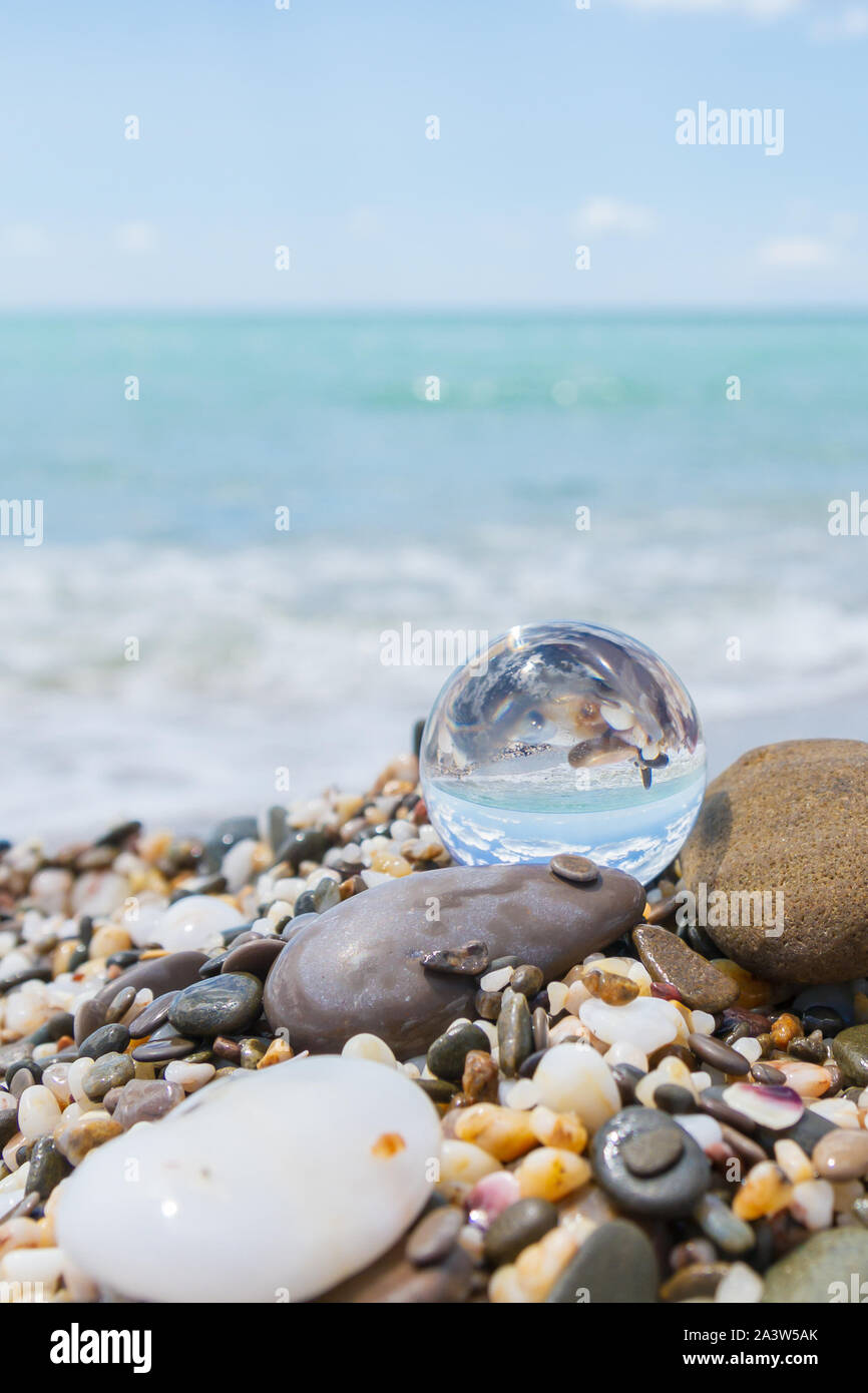 Glass round ball on the beach reflects the sea in summer Stock Photo ...