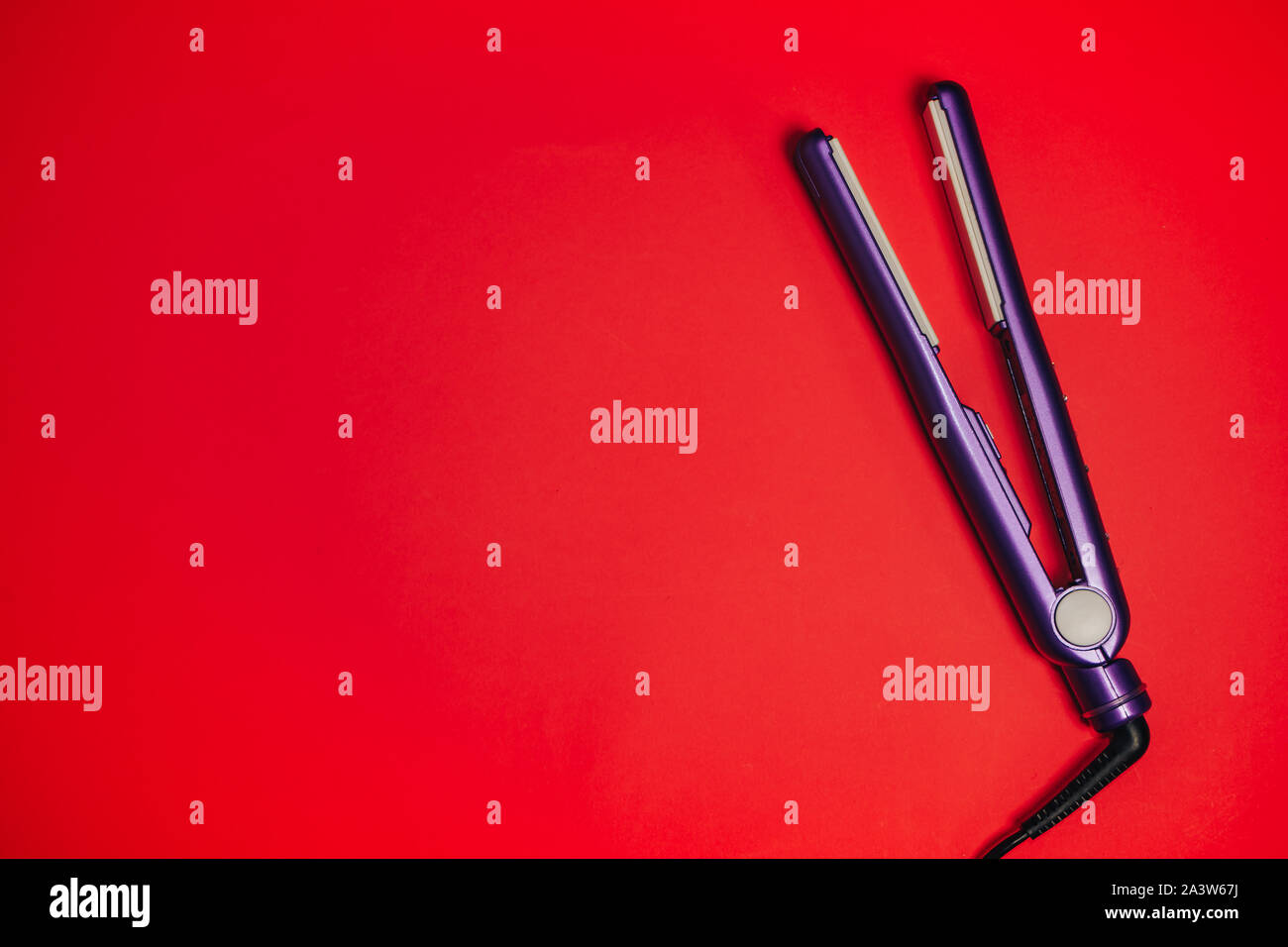 Beautiful hair straightener purple on a red background table. top view ...