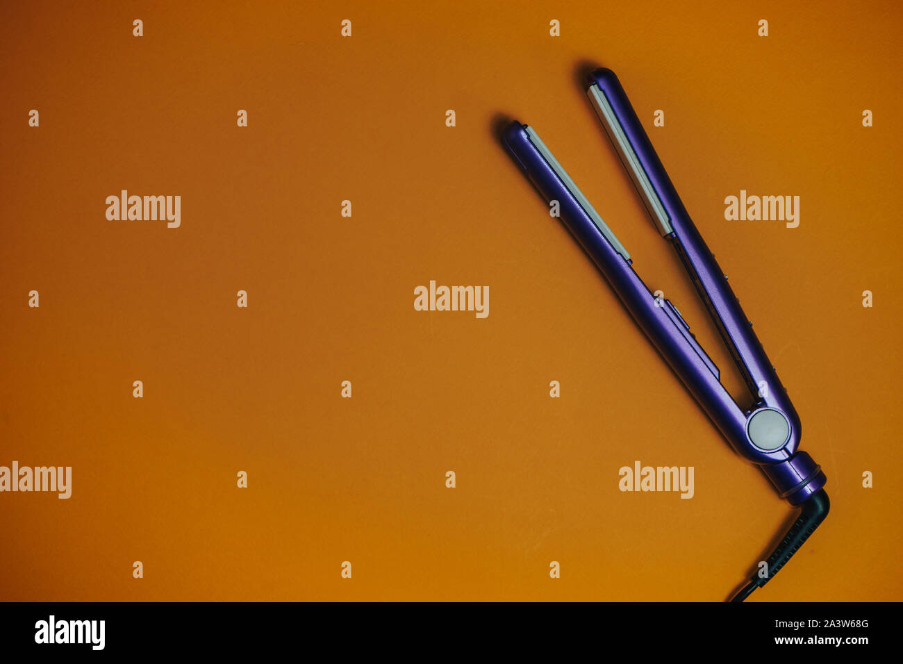 Beautiful hair straightener purple on a orange background table. top ...