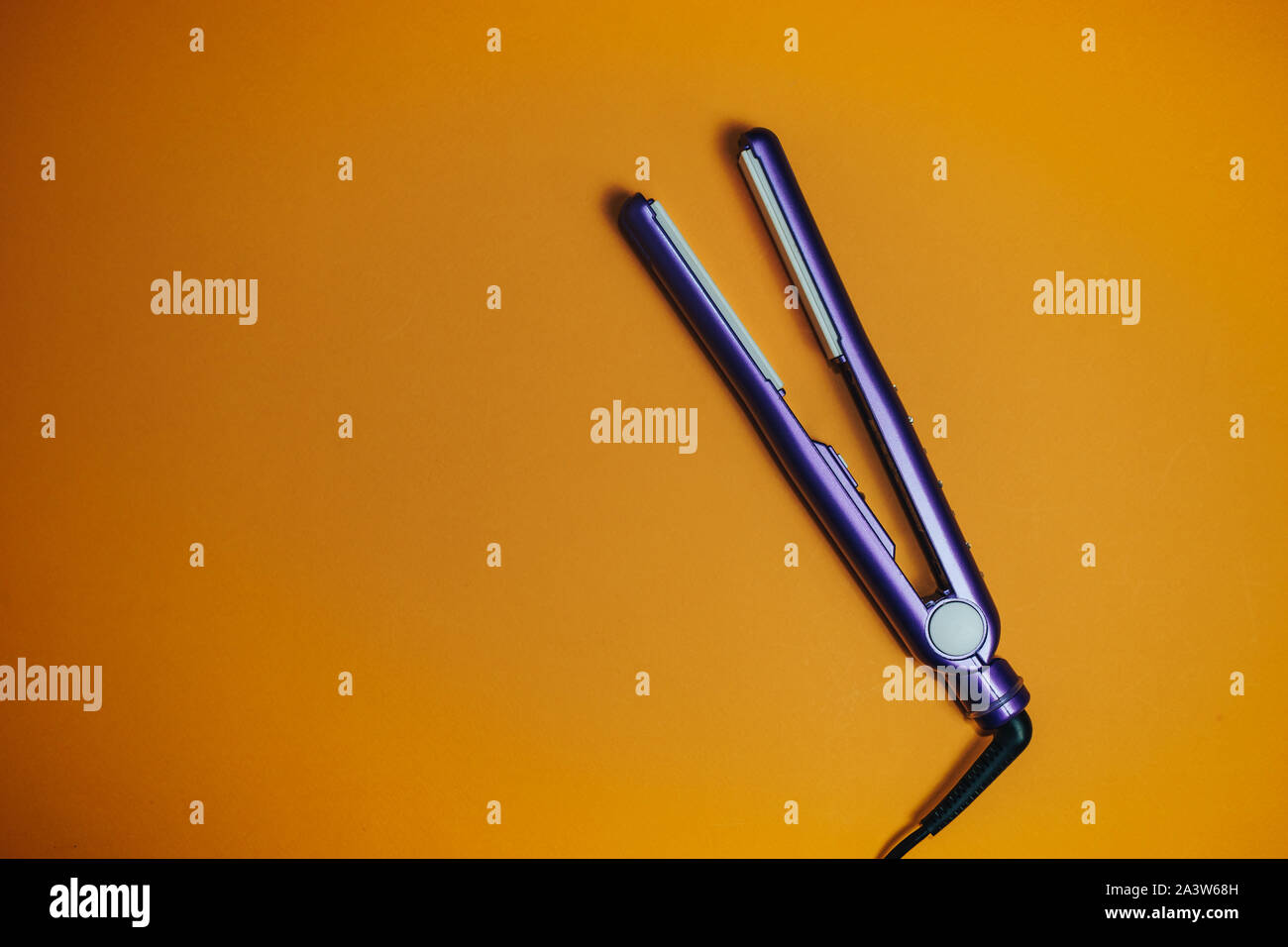 Beautiful hair straightener purple on a orange background table. top ...