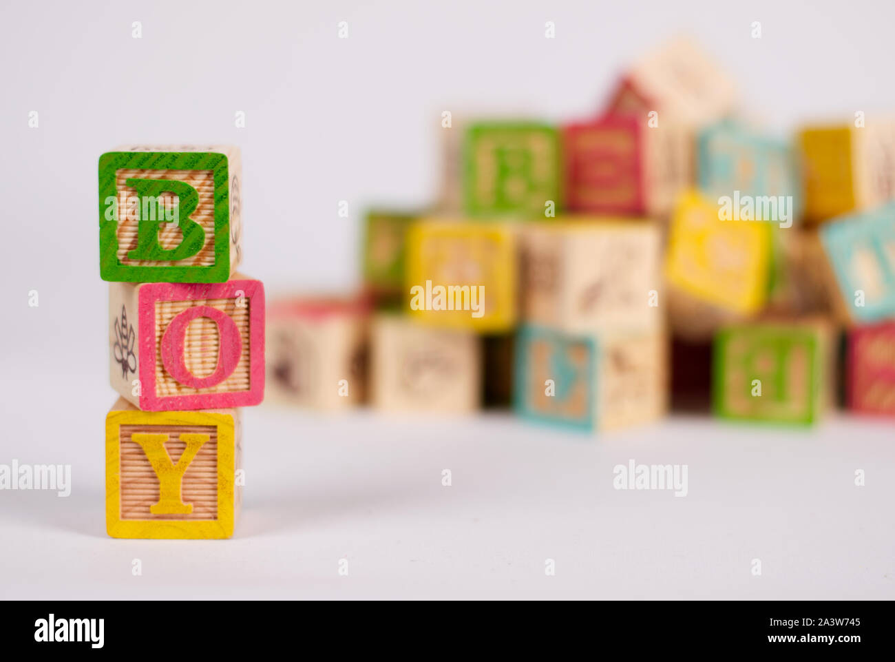 The word 'BOY' in coloured wooden blocks, with a grey background ...