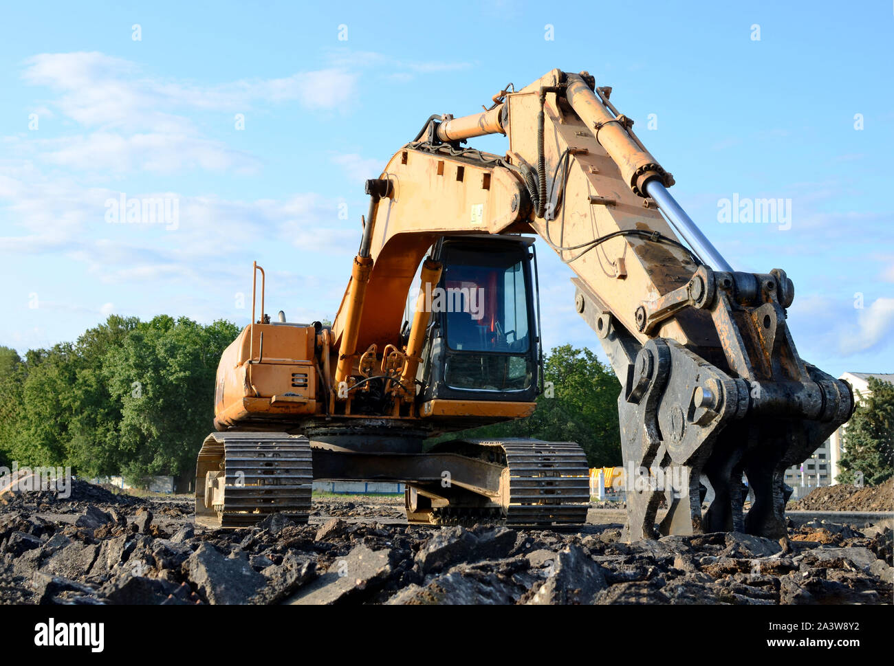 Excavator with hydraulic shears breaks asphalt on a construction site ...