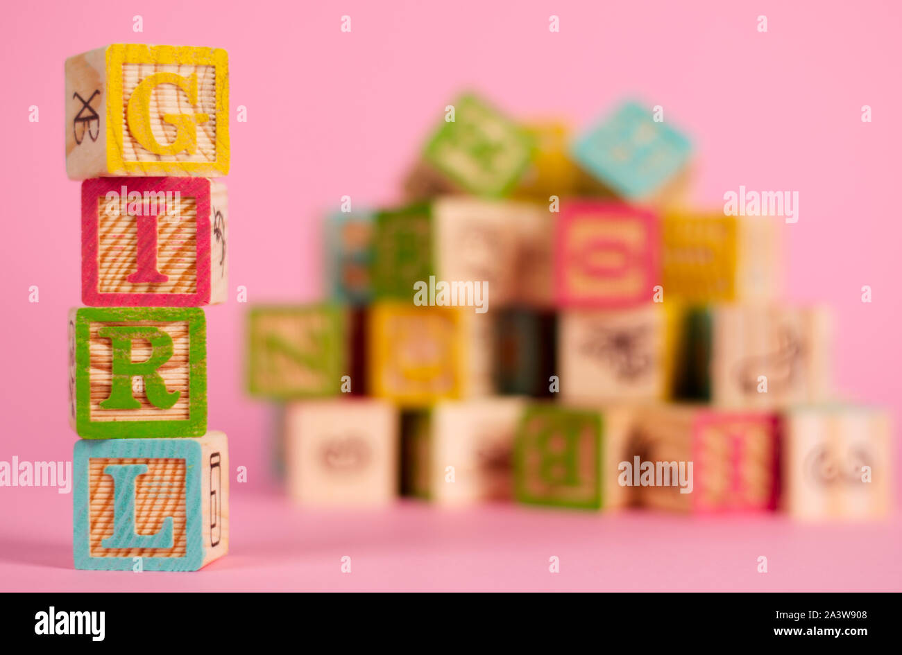 The word 'GIRL' in coloured wooden blocks, with a pink background ...