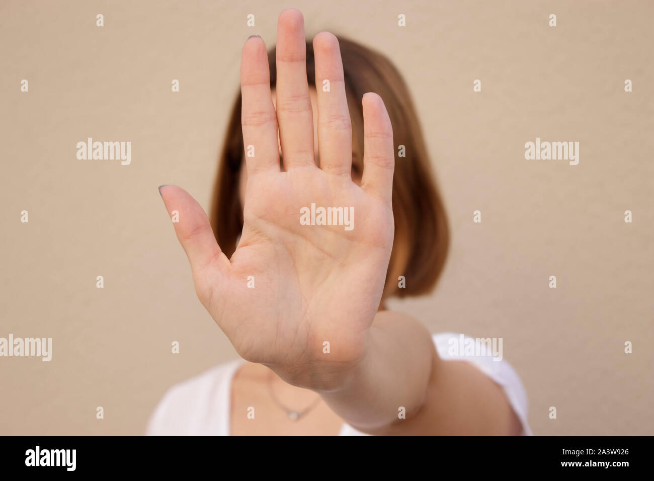 Serious young woman showing stop hand sign, on isolated background ...