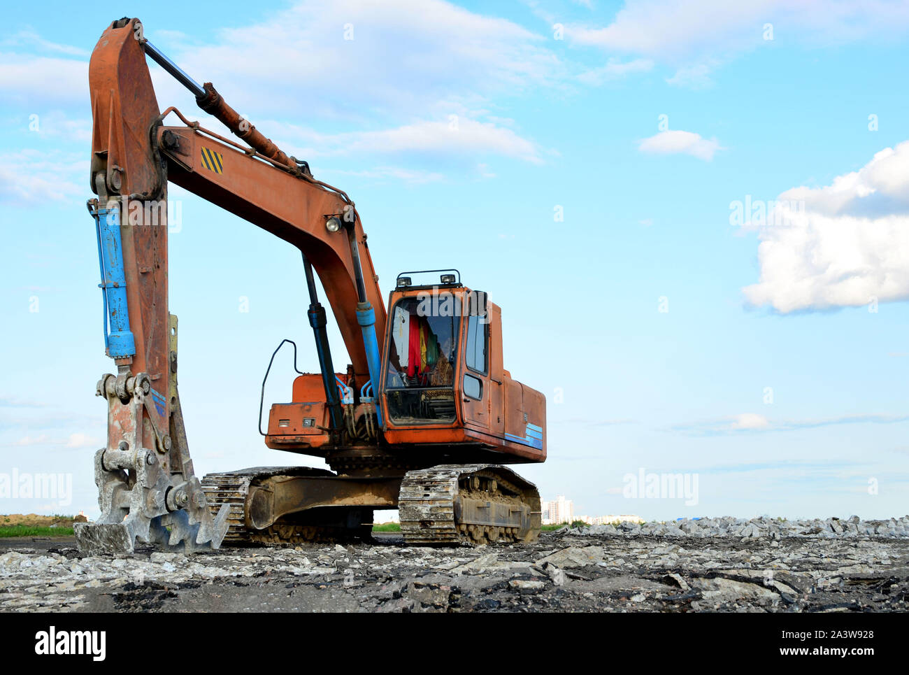 Excavator with hydraulic shears breaks asphalt on a construction site ...