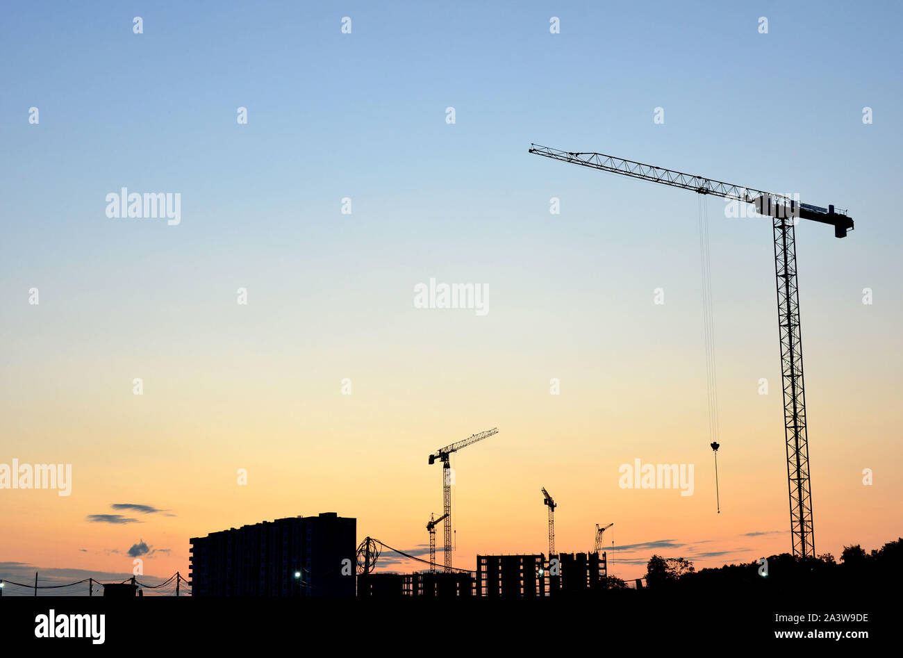 Jib construction tower cranes at a construction site on the sunset and ...