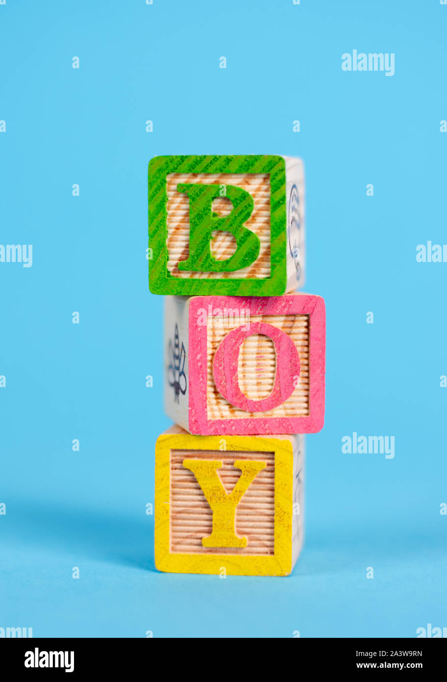 The word 'BOY' in coloured wooden blocks, with a blue background ...