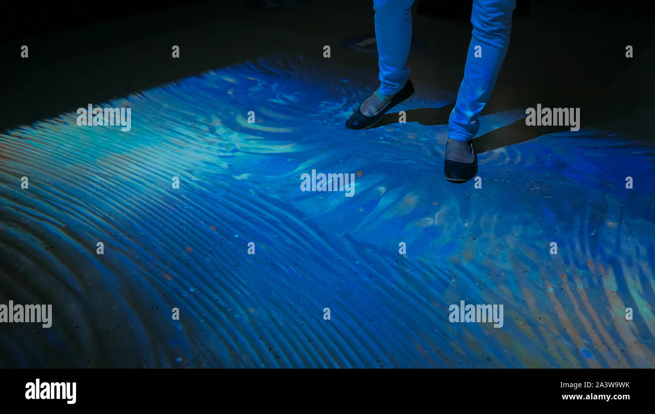 Woman walking on interactive water surface Stock Photo - Alamy