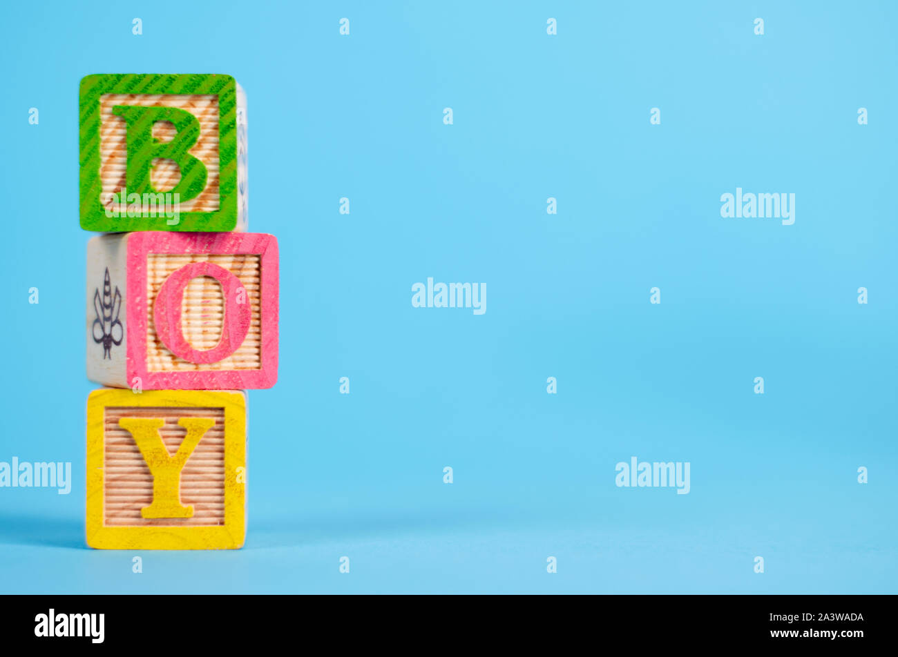 The word 'BOY' in coloured wooden blocks, with a blue background ...
