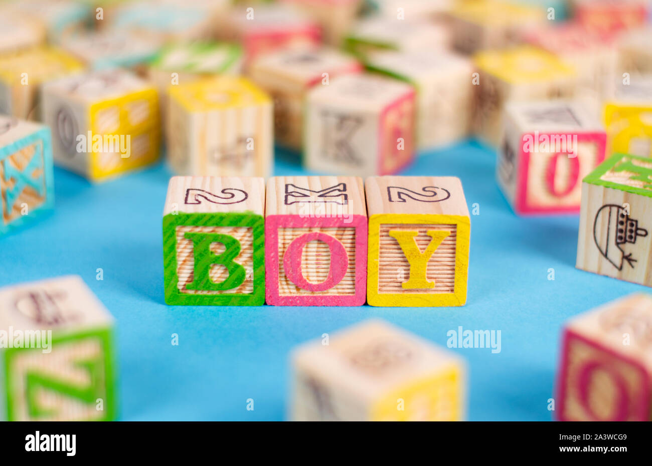 The word 'BOY' in coloured wooden blocks, with a blue background ...