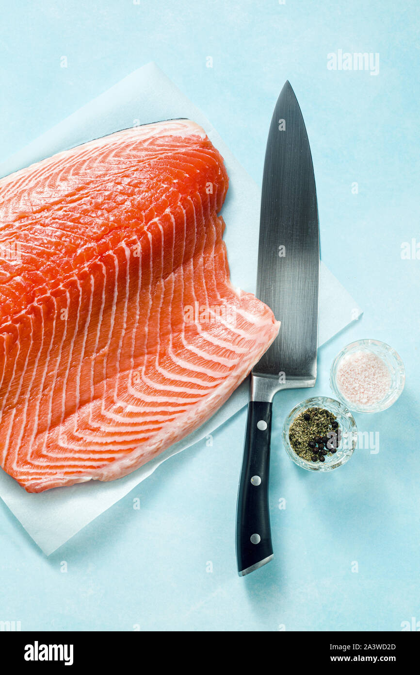 Fresh salmon slice on a wooden cutting board with a chef's knife on the ...