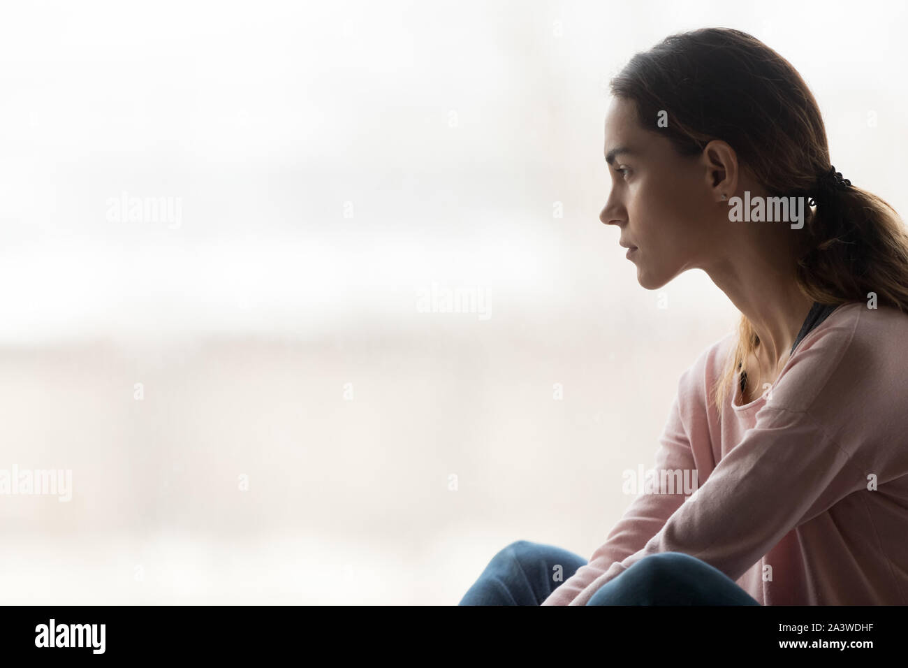 Thoughtful pensive girl sitting alone looking through window Stock ...