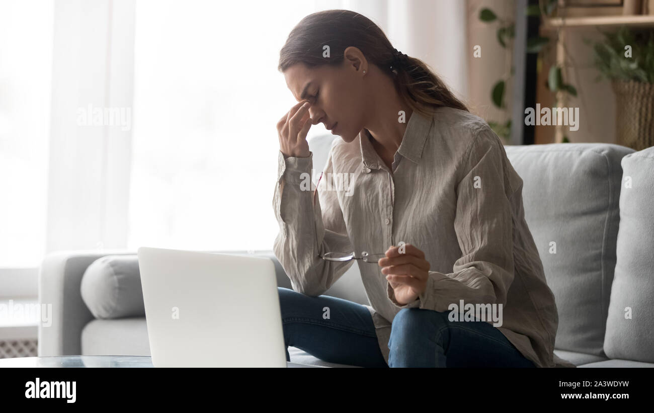 Tired young woman holding glasses feel eyestrain after computer work ...