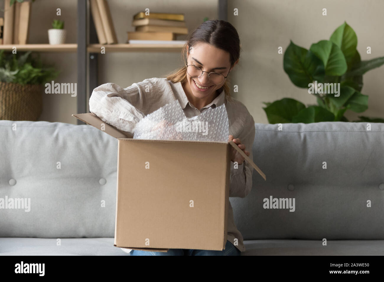 Smiling young woman customer unpack box open parcel at home Stock Photo ...