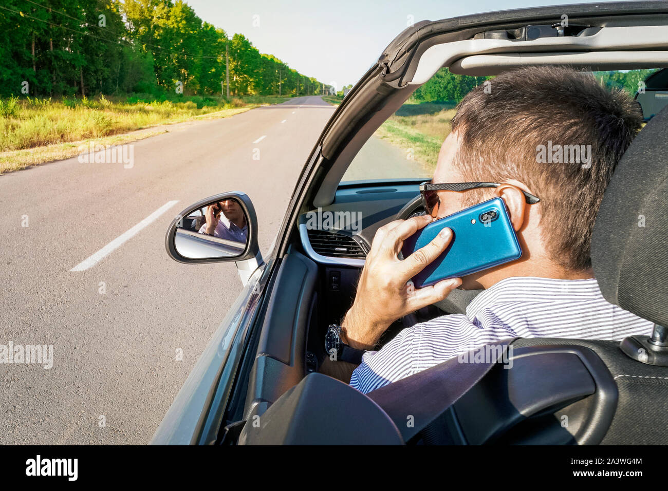 guy behind wheel of car talking on phone and looking at road with an ...